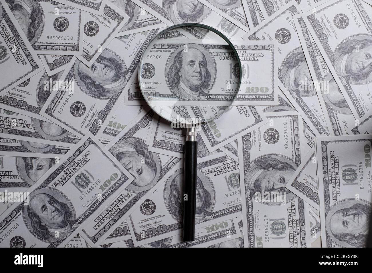 Magnifying glass on a pile of hundred us dollar money Stock Photo - Alamy