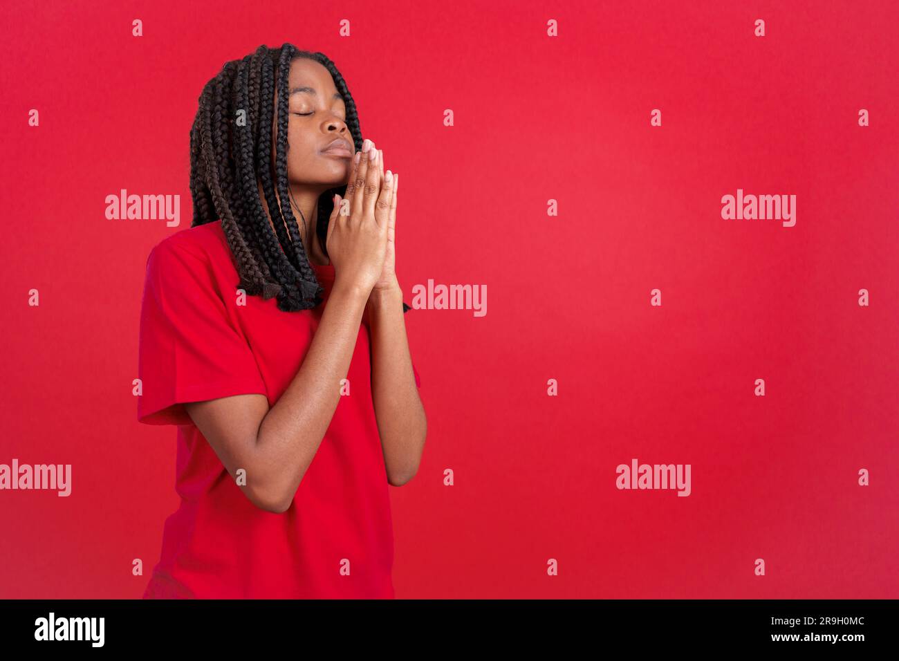 African woman standing and praying with eyes closed Stock Photo - Alamy