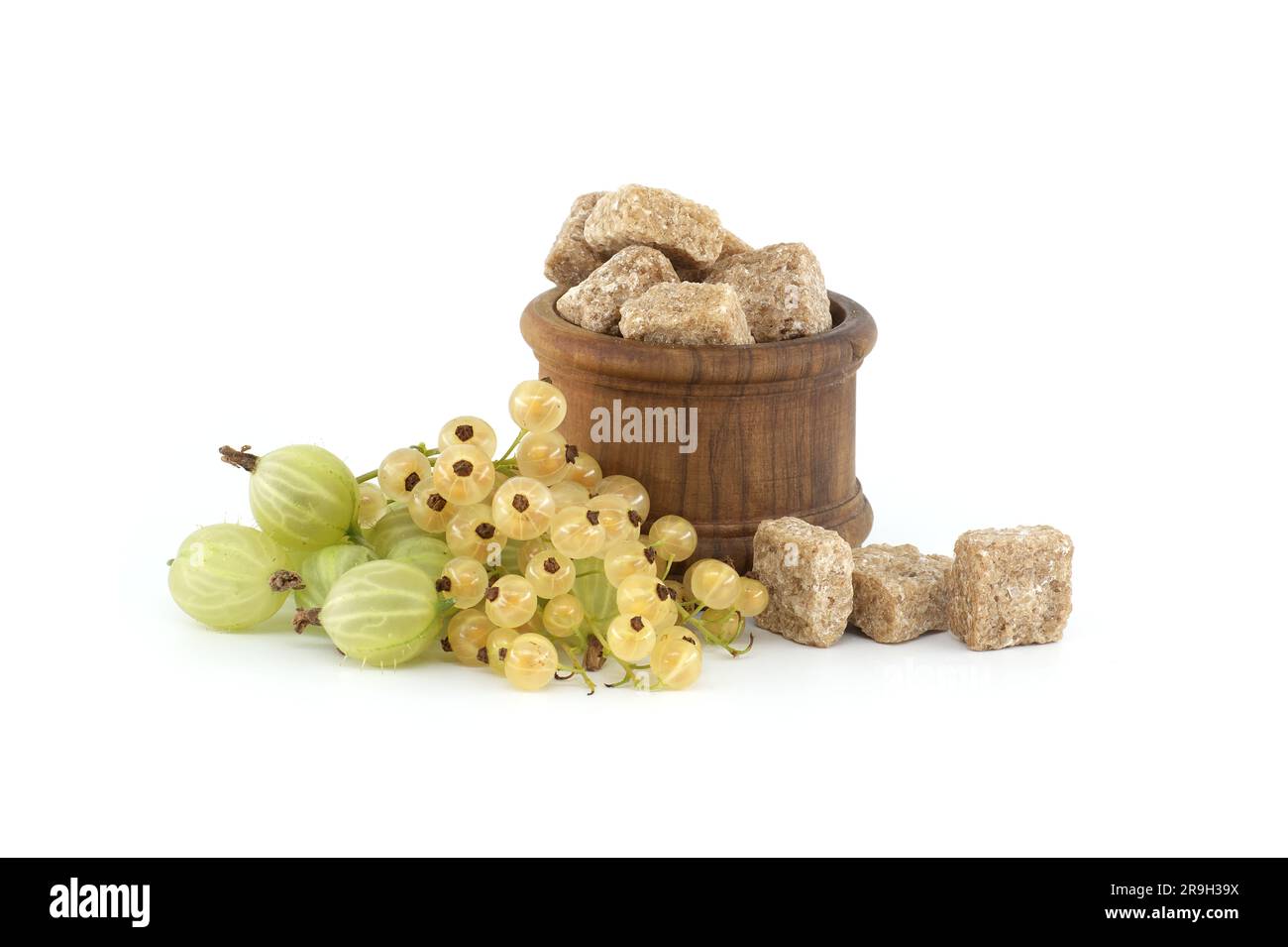 Gooseberries and yellow currants next to brown cane sugar cubes in ...