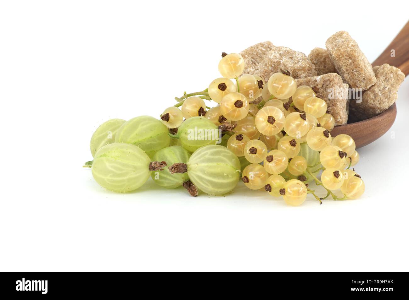 Gooseberries and yellow currants next to brown cane sugar cubes in ...