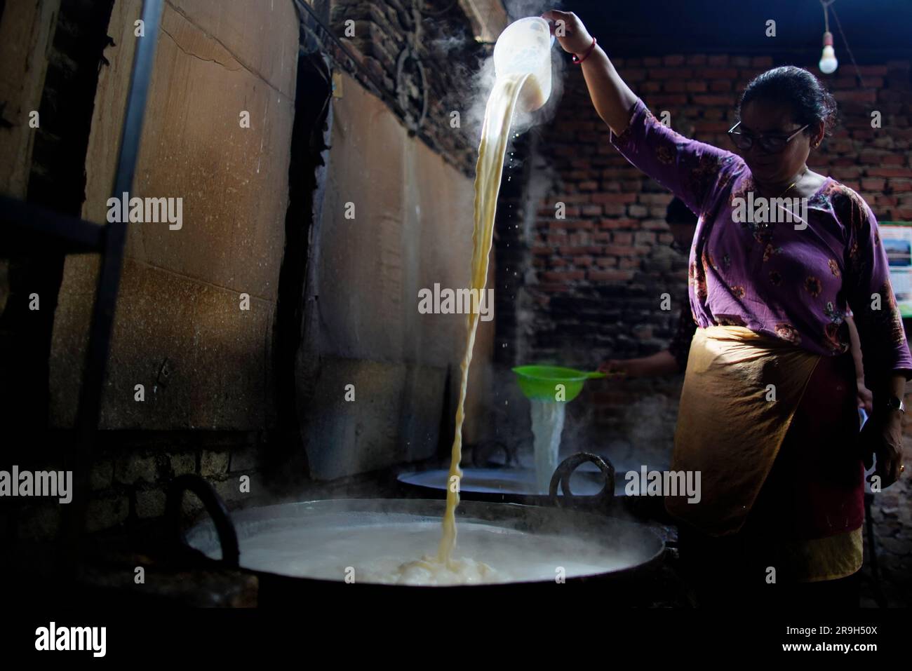 Bhaktapur, Nepal. 27th June, 2023. A woman boils milk to make curd ...