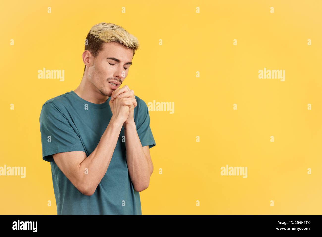 Gay man praying with eyes closed and folded hands Stock Photo - Alamy