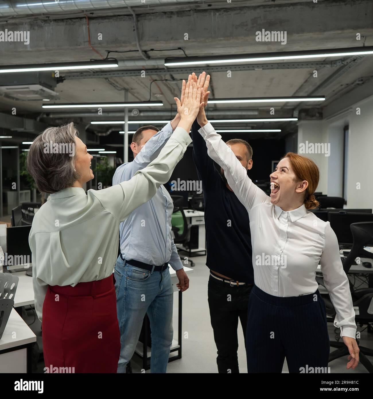 Four co-workers give a high five in the office Stock Photo - Alamy