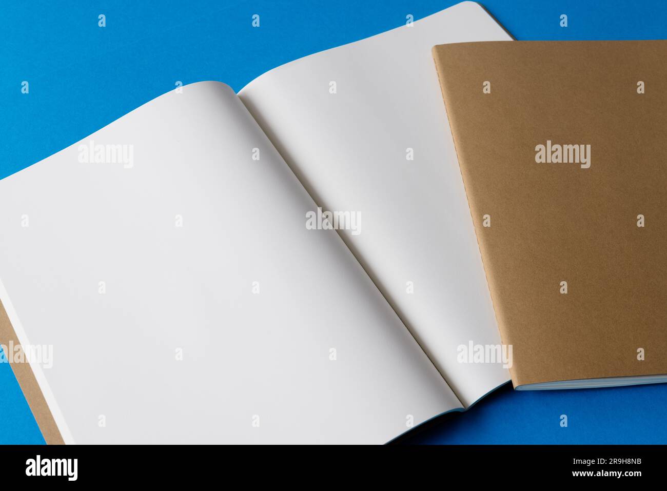 Close up of beige notebook and open book with copy space on blue ...
