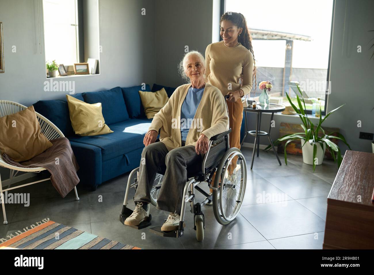 Teenage girl pushing wheelchair with her grandmother while walking ...