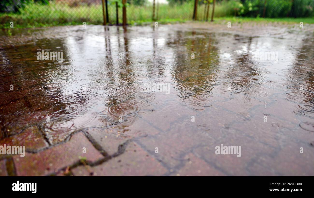 Drops of heavy rain on sidewalk surface. Rain water on the surface of ...