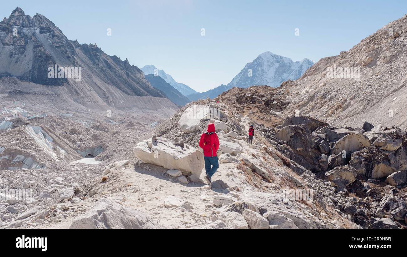 Two people walking up a winding path surrounded by towering mountains ...