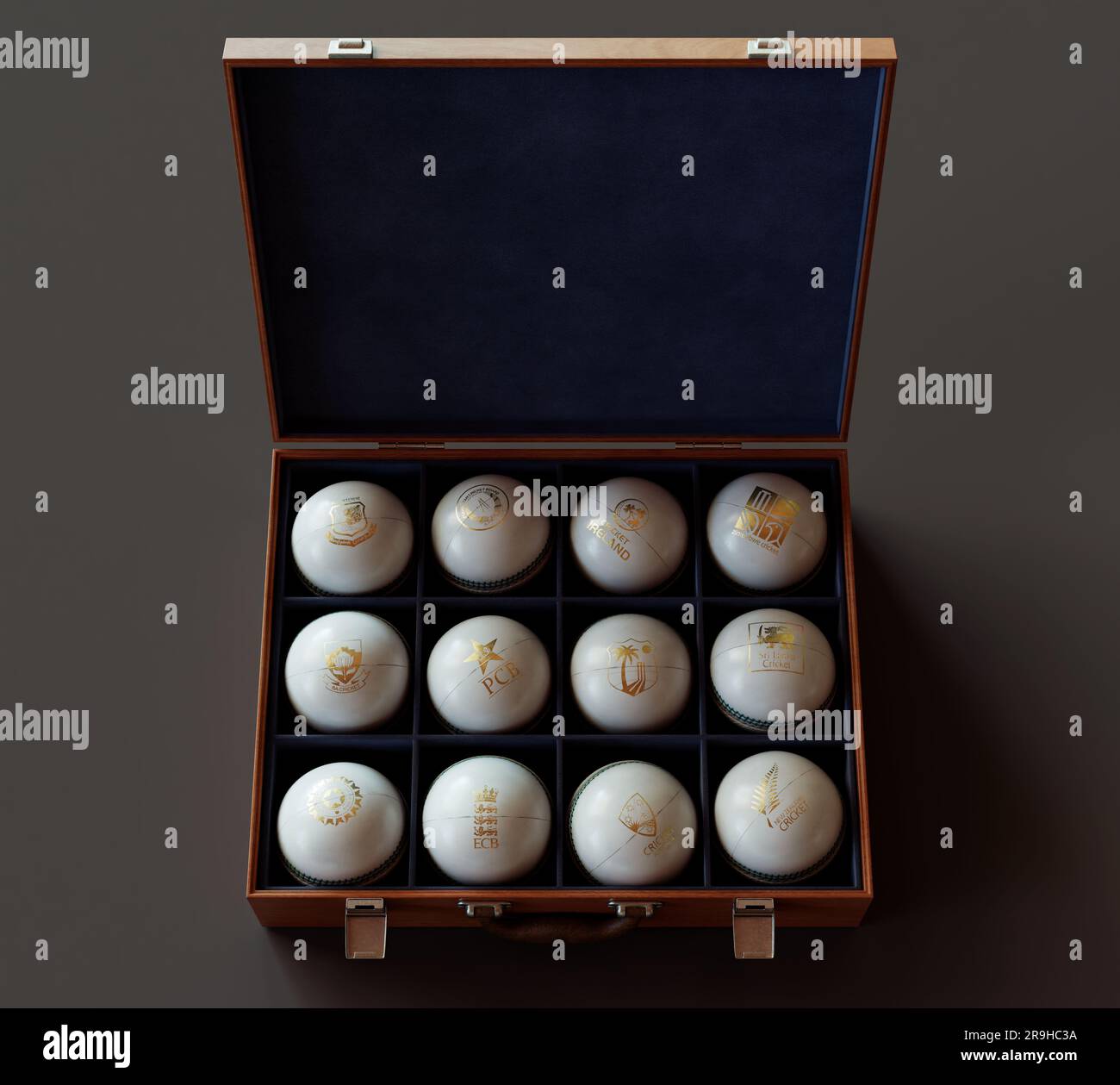 A collection of white cricket balls imprinted with gold logos of the ...