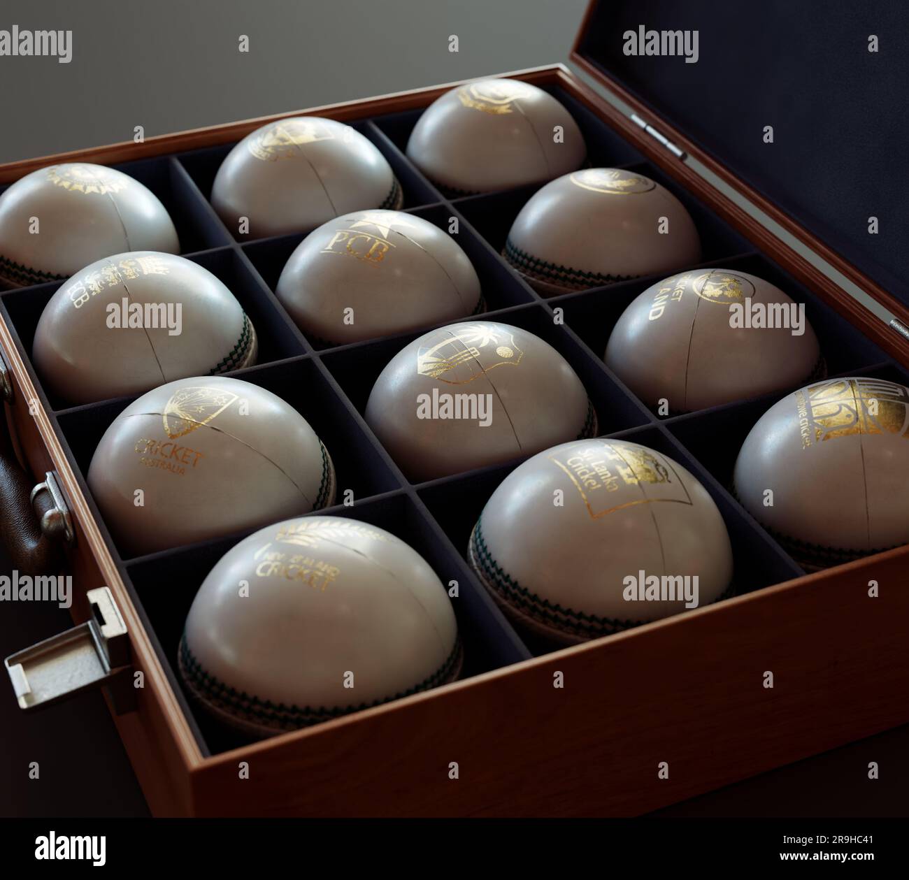 A collection of white cricket balls imprinted with gold logos of the ...