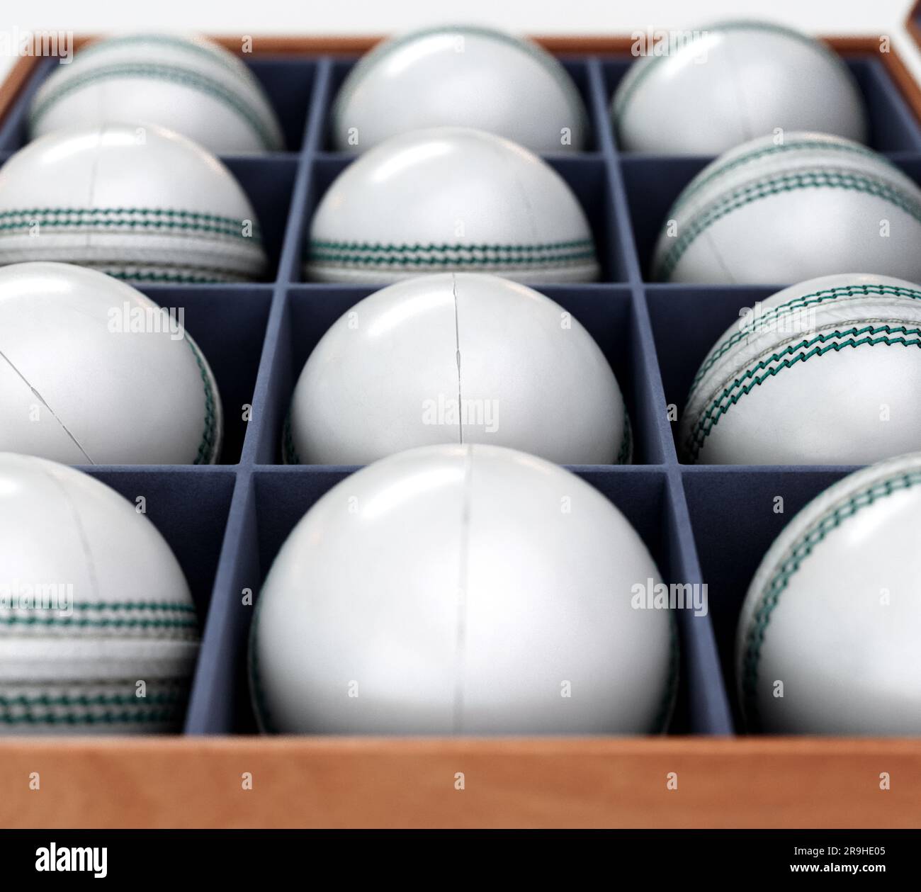 Twelve generic white cricket balls in a wooden display box lined with ...