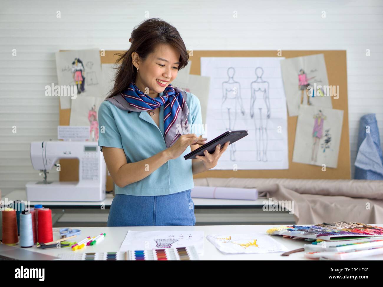 Young asian dressmaker in striped scarf checking email order from ...