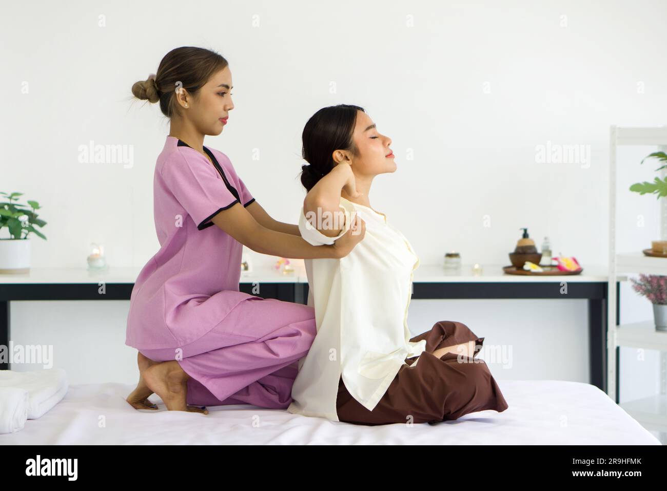 Cute girl with traditional dress stretch back and shoulder by massager ...