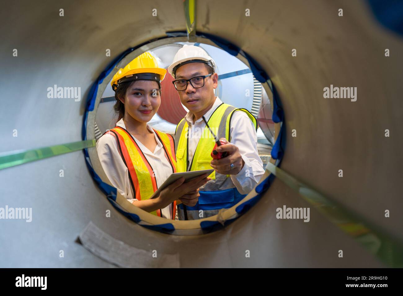 Asian male and female factory worker inspecting quality rolls of metal ...