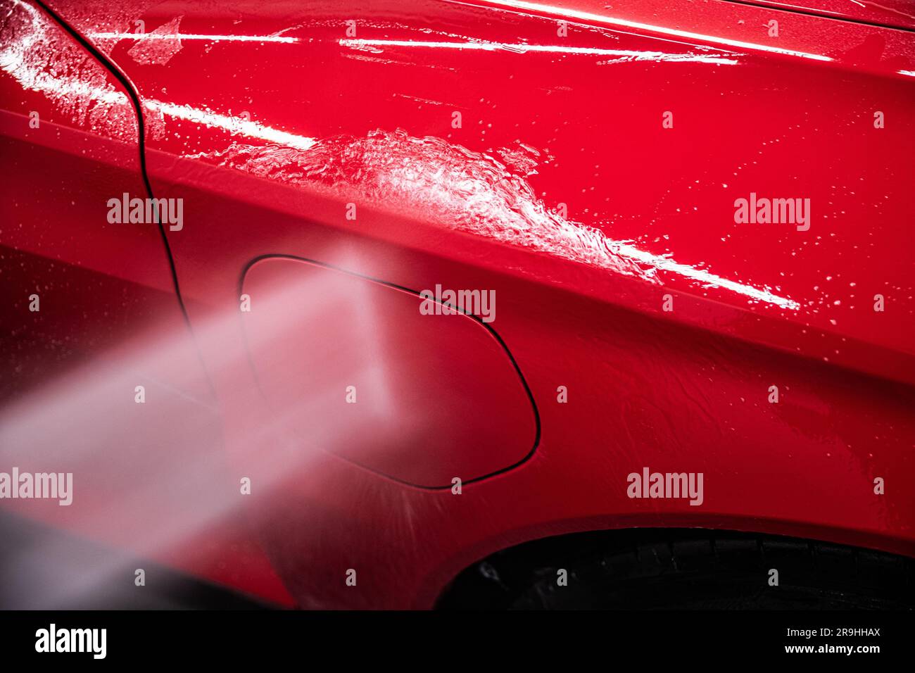 Washing a modern red car at a car wash using a pressure washer Stock ...
