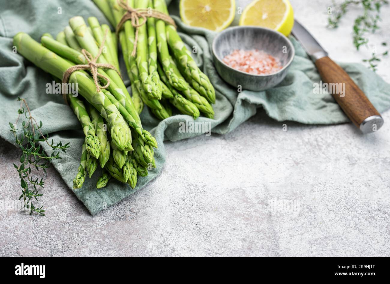 Bunch of raw asparagus stems with different spices on grey concrete ...