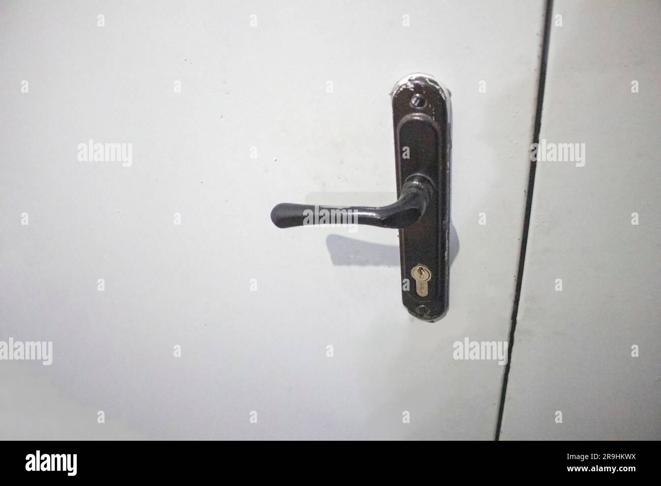 White close metal door with a dark handle for an exit Stock Photo - Alamy