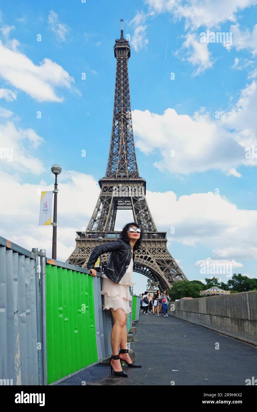 A street fashion blogger poses with the Eiffel Tower in Paris France, a ...