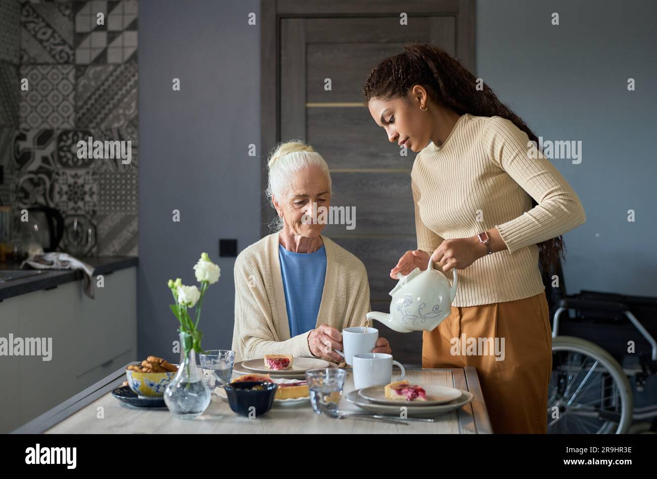 Cute teenage girl with porcelain teapot pouring tea into cup of her ...