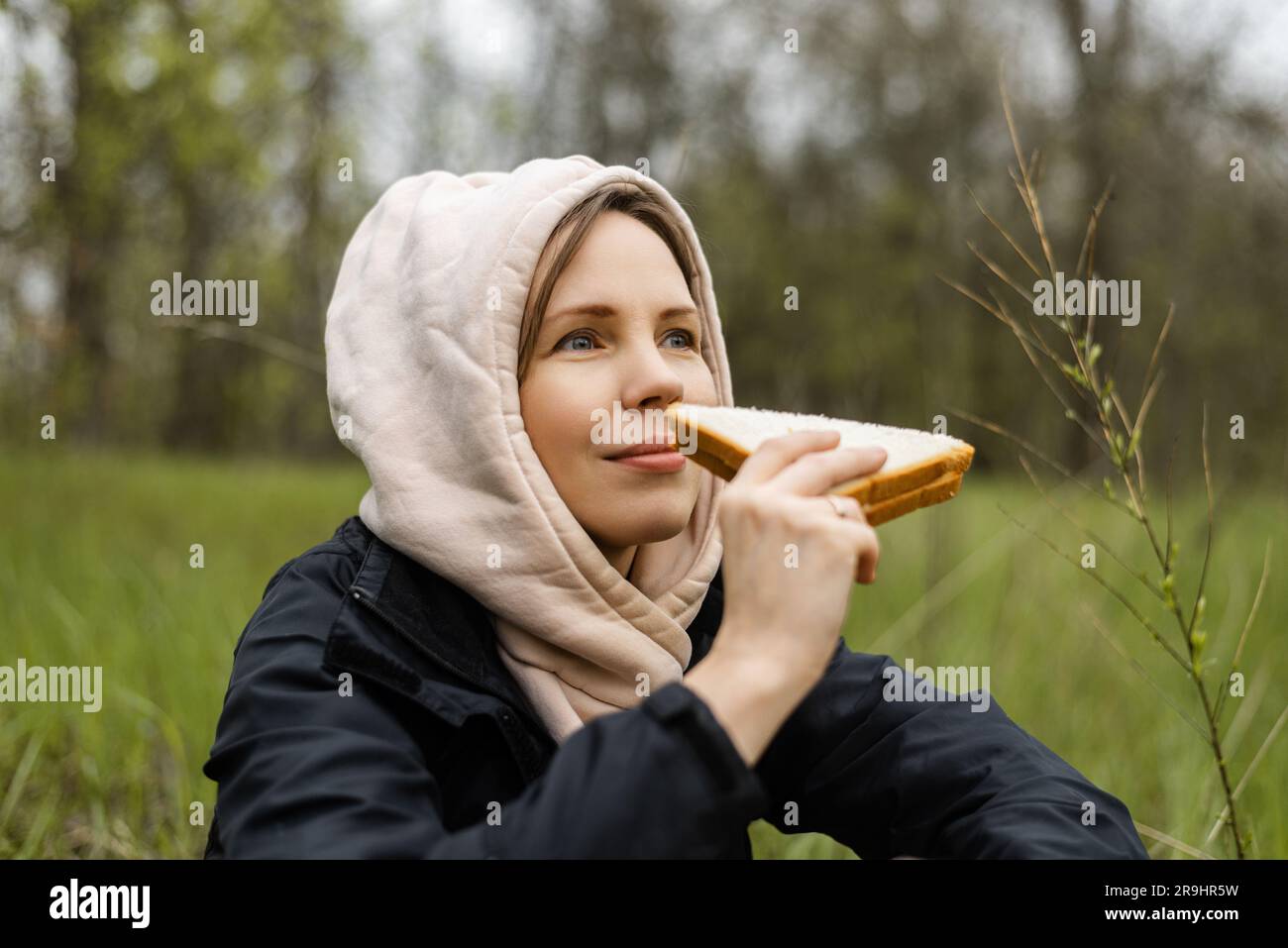 An adult attractive woman eats a sandwich outdoors in the forest, park ...