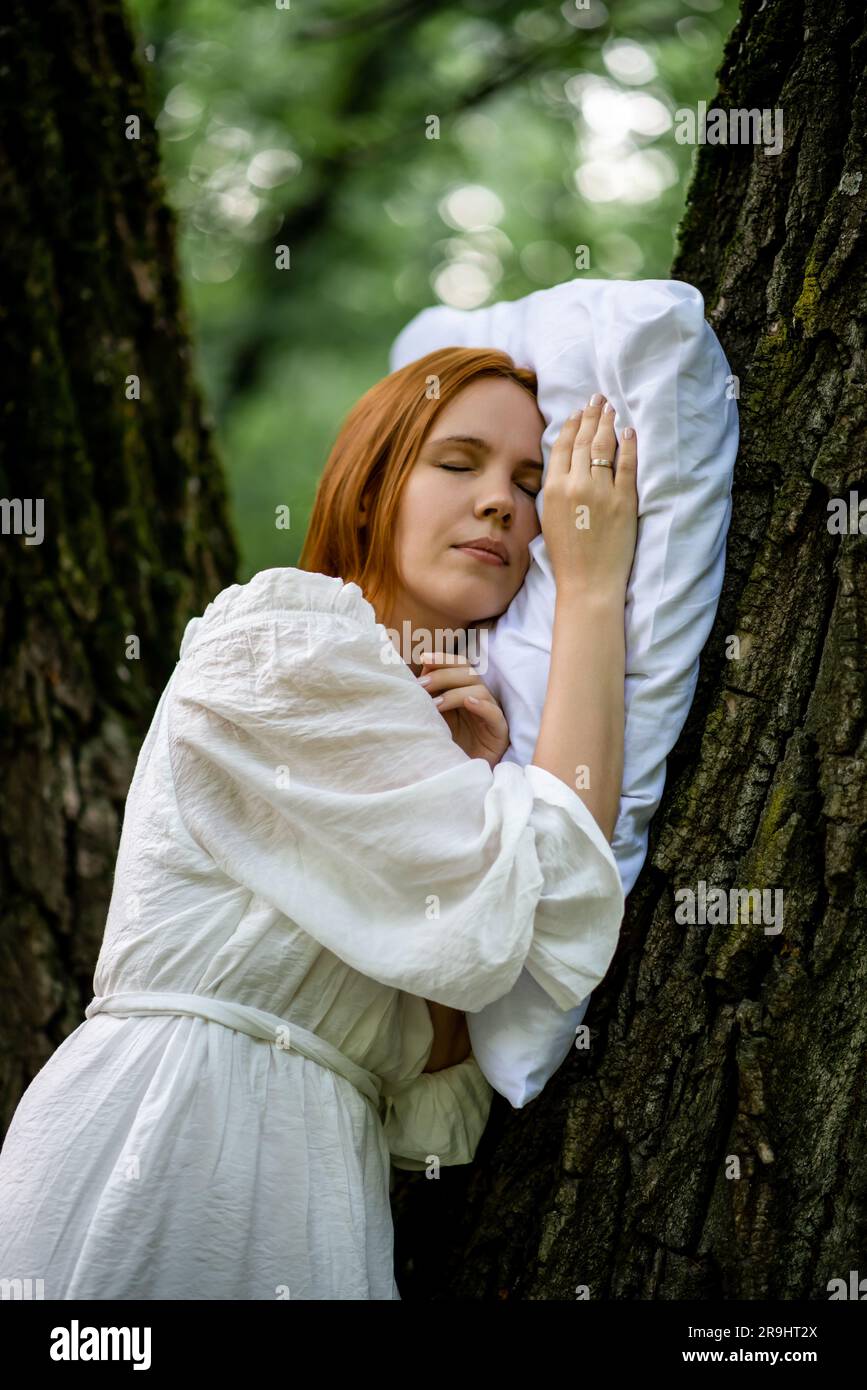Woman sleeps soundly outdoors. She is lying on a pillow on a tree ...