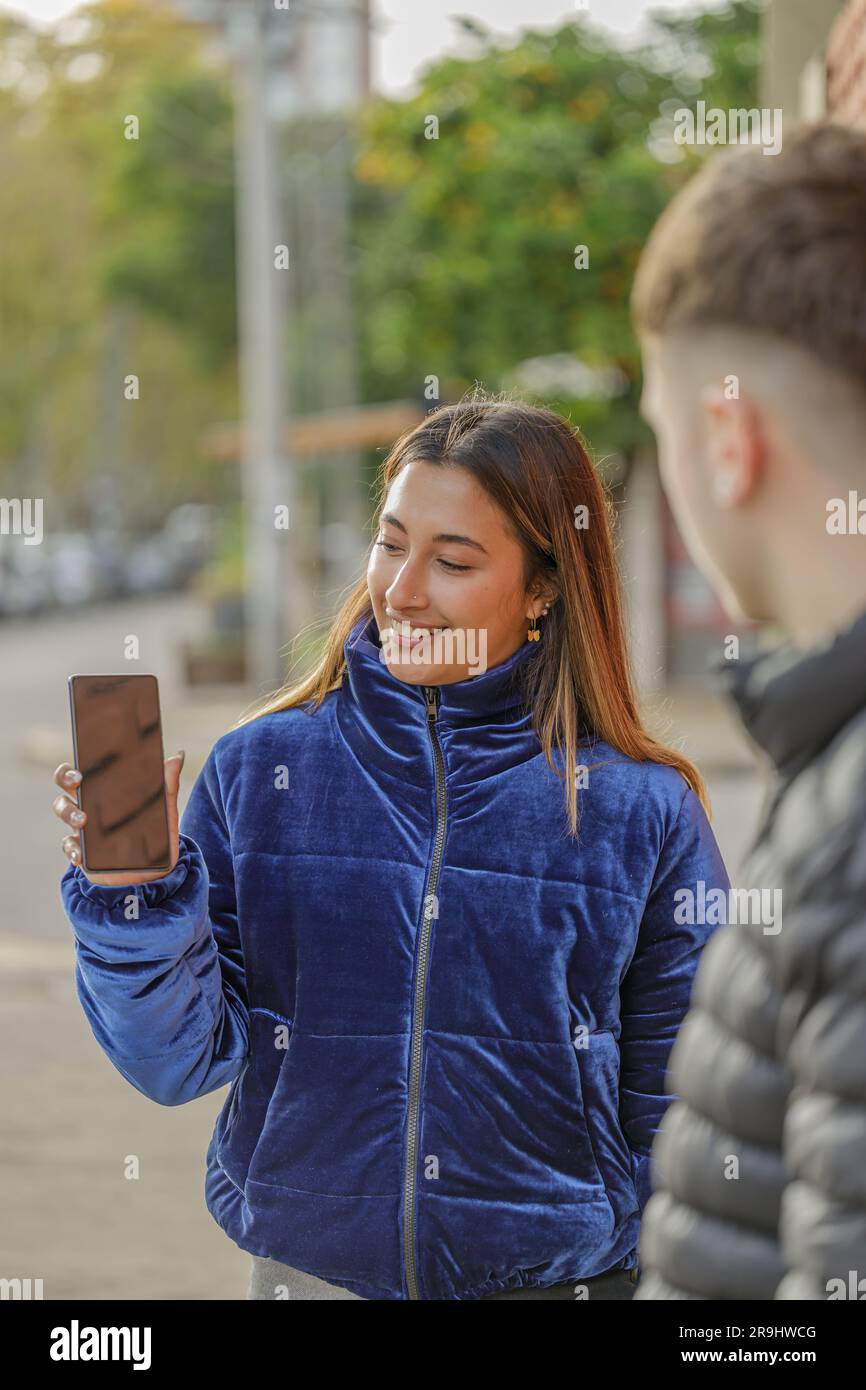 Girl shows her mobile phone to a guy Stock Photo - Alamy
