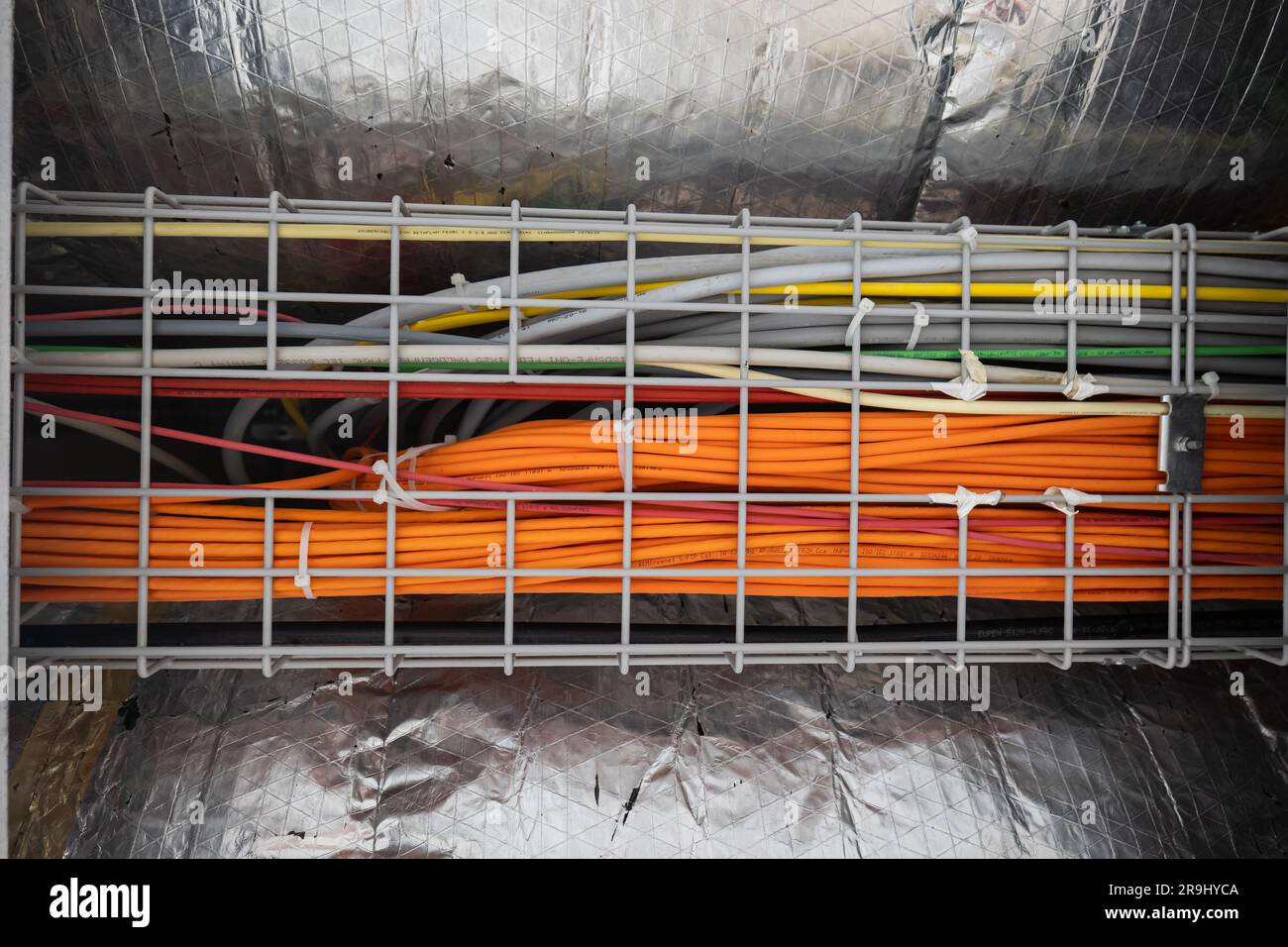 Bundle of orange ethernet cables routed in a building ceiling along the ...