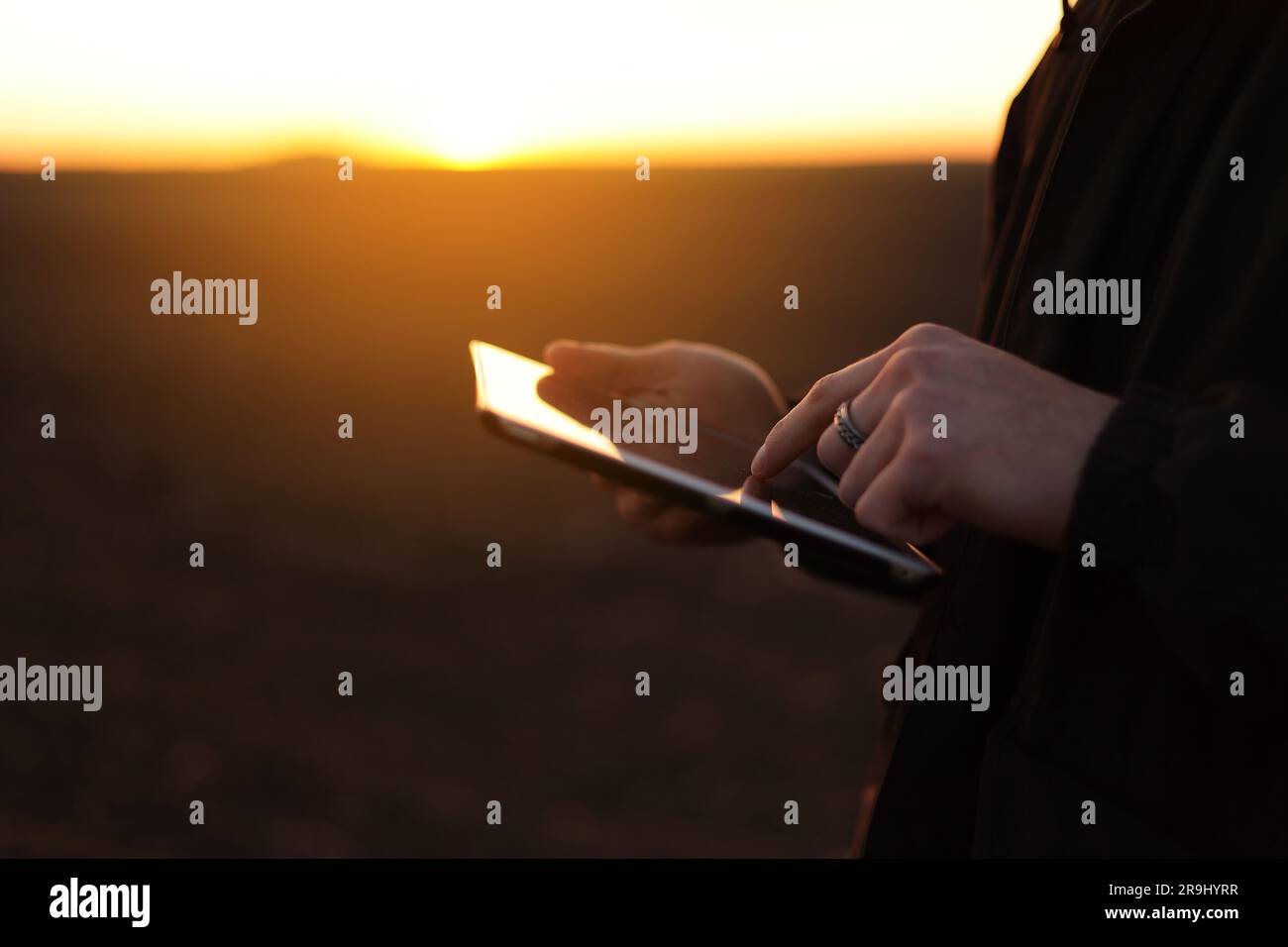 Cropped shot of male farmer's hands use digital tablet on plowed field ...