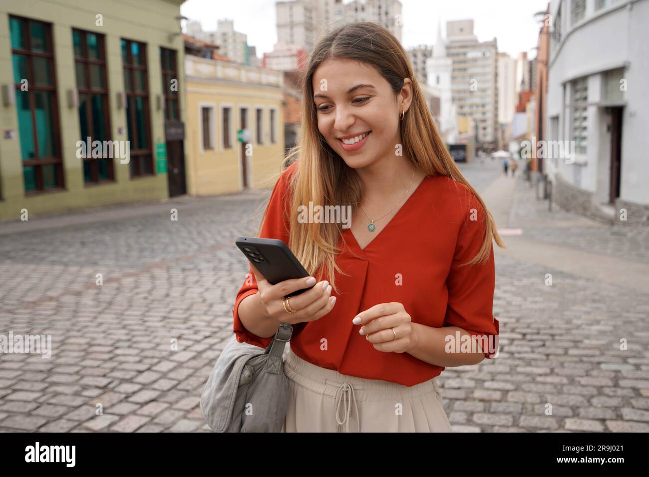 Brazilian young lady using mobile phone in city street of Curitiba ...