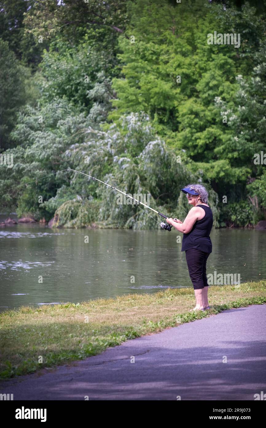 A middle aged woman fishes at the lake in Kissena Park, Flushing ...