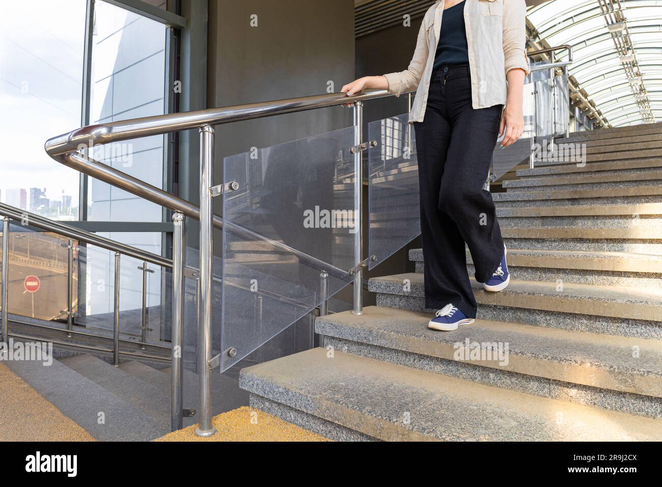 woman walking down the stairs holding onto the railing. a woman walks ...