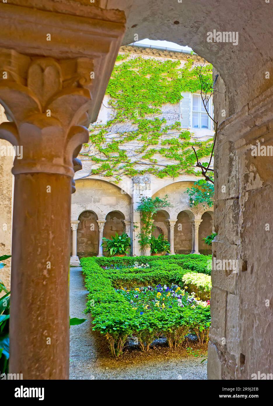 The carved stone columns and small topiary garden in cloister of Saint ...