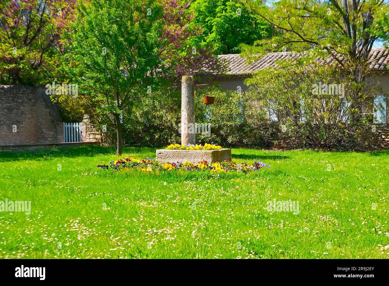 The ancient column surrounded with bright pansy flowers amid the lawn ...