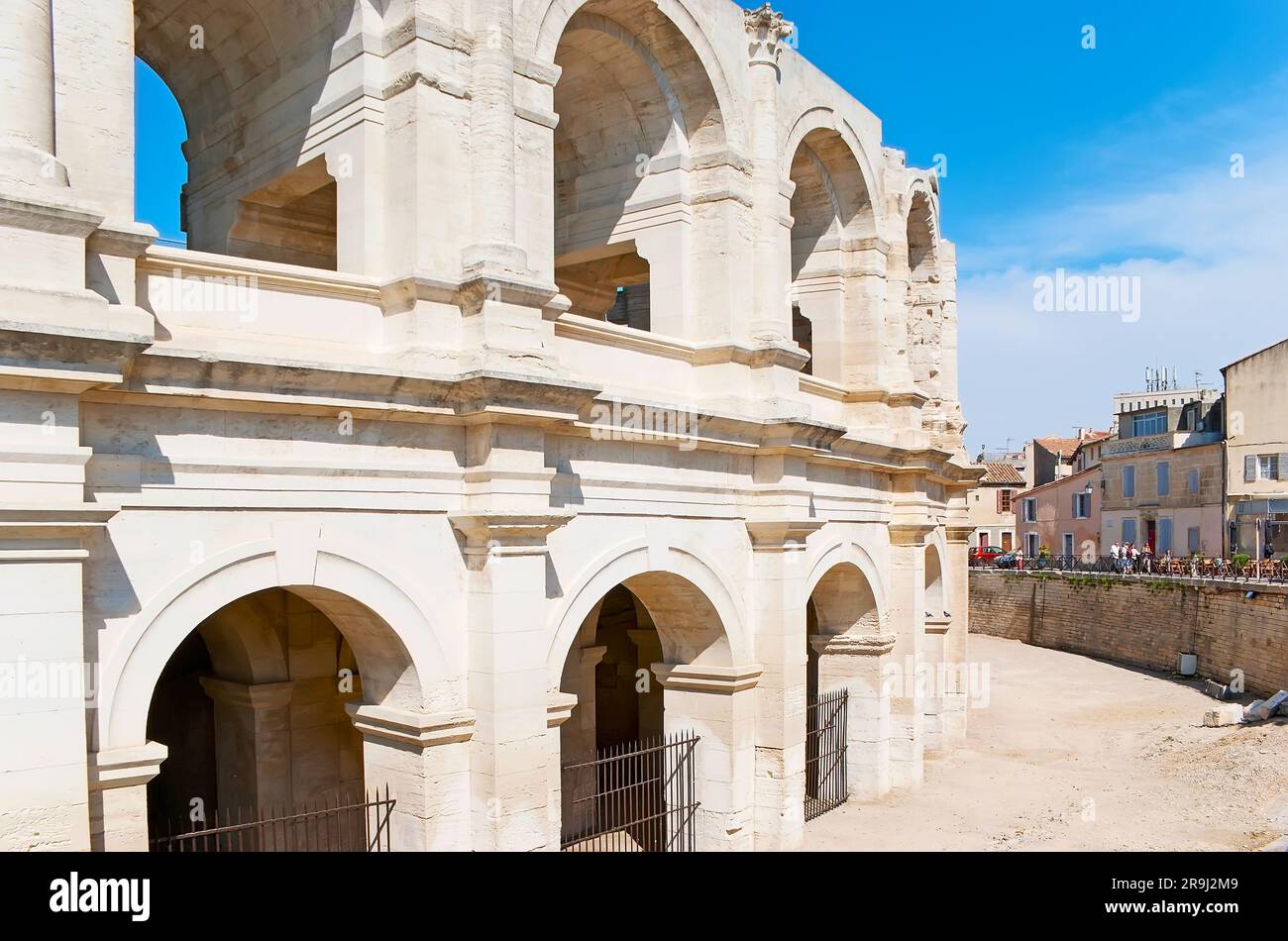 The white stone wall with arched windows of the Amphitheatre of Arles ...