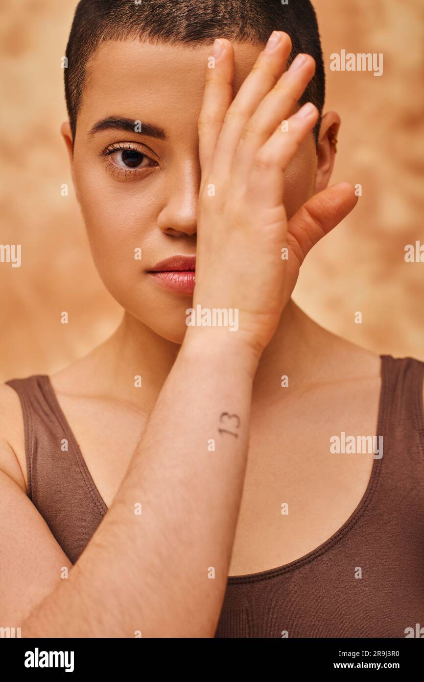 natural look, tattooed young woman with short hair posing on mottled ...