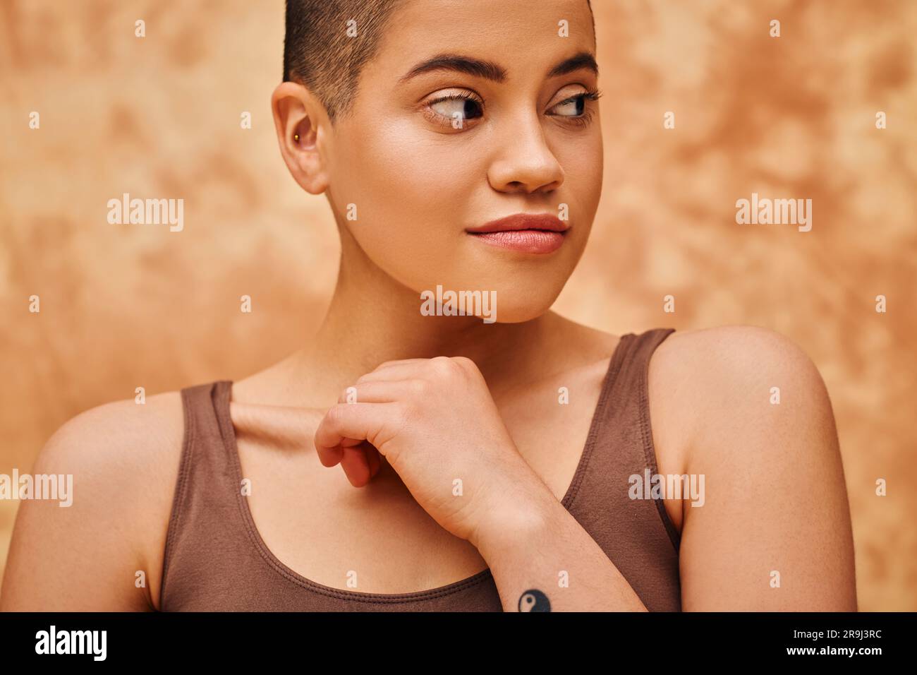 natural look, tattooed young woman with short hair posing on mottled ...
