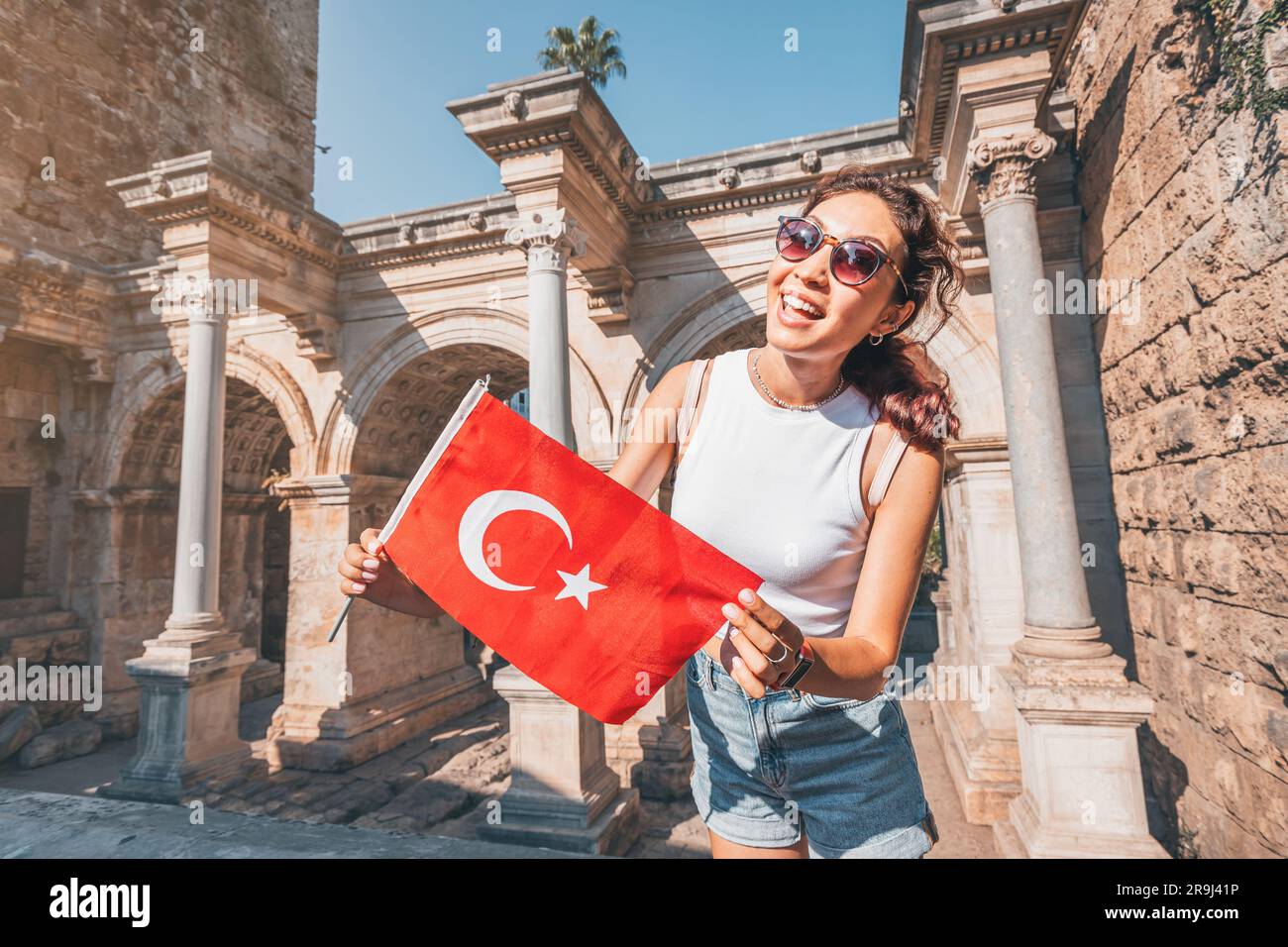 Happy traveller girl with turkish flag in hand and famous gate or ...