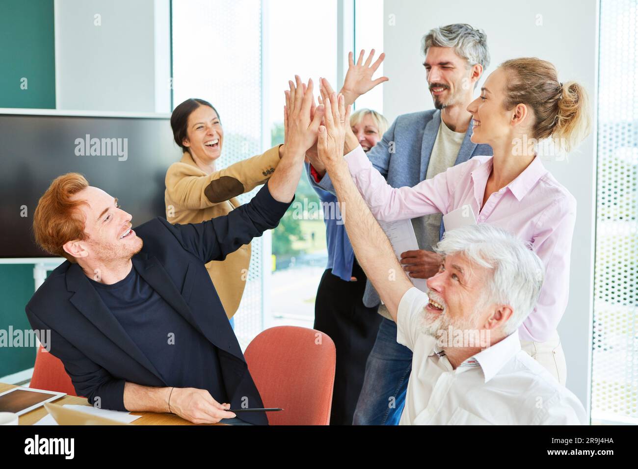 Happy business people as team giving high five for motivation in the office Stock Photo - Alamy