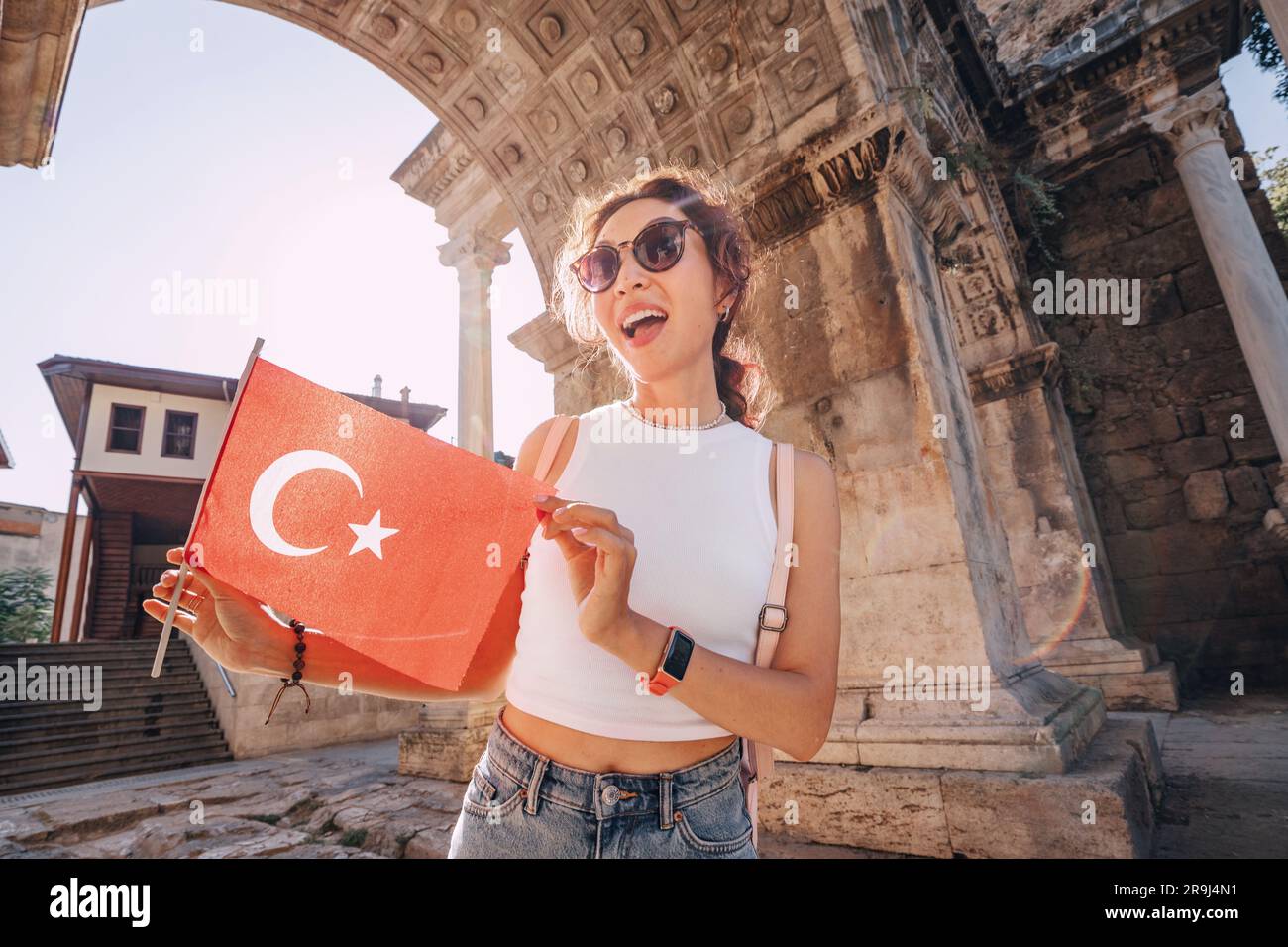 Happy traveller girl with turkish flag in hand and famous gate or ...