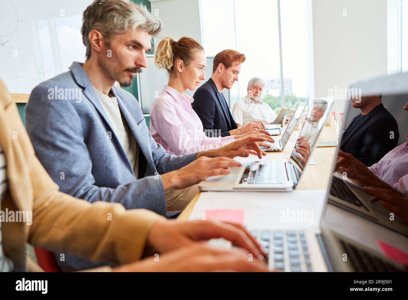 Dedicated male and female executives using laptops at workplace Stock ...