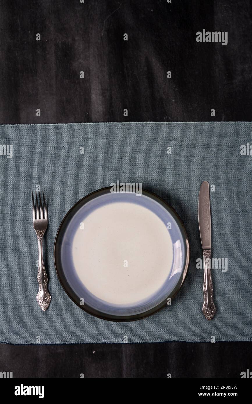 Blue table cloth with a plate on black chalkboard background. Flat lay ...