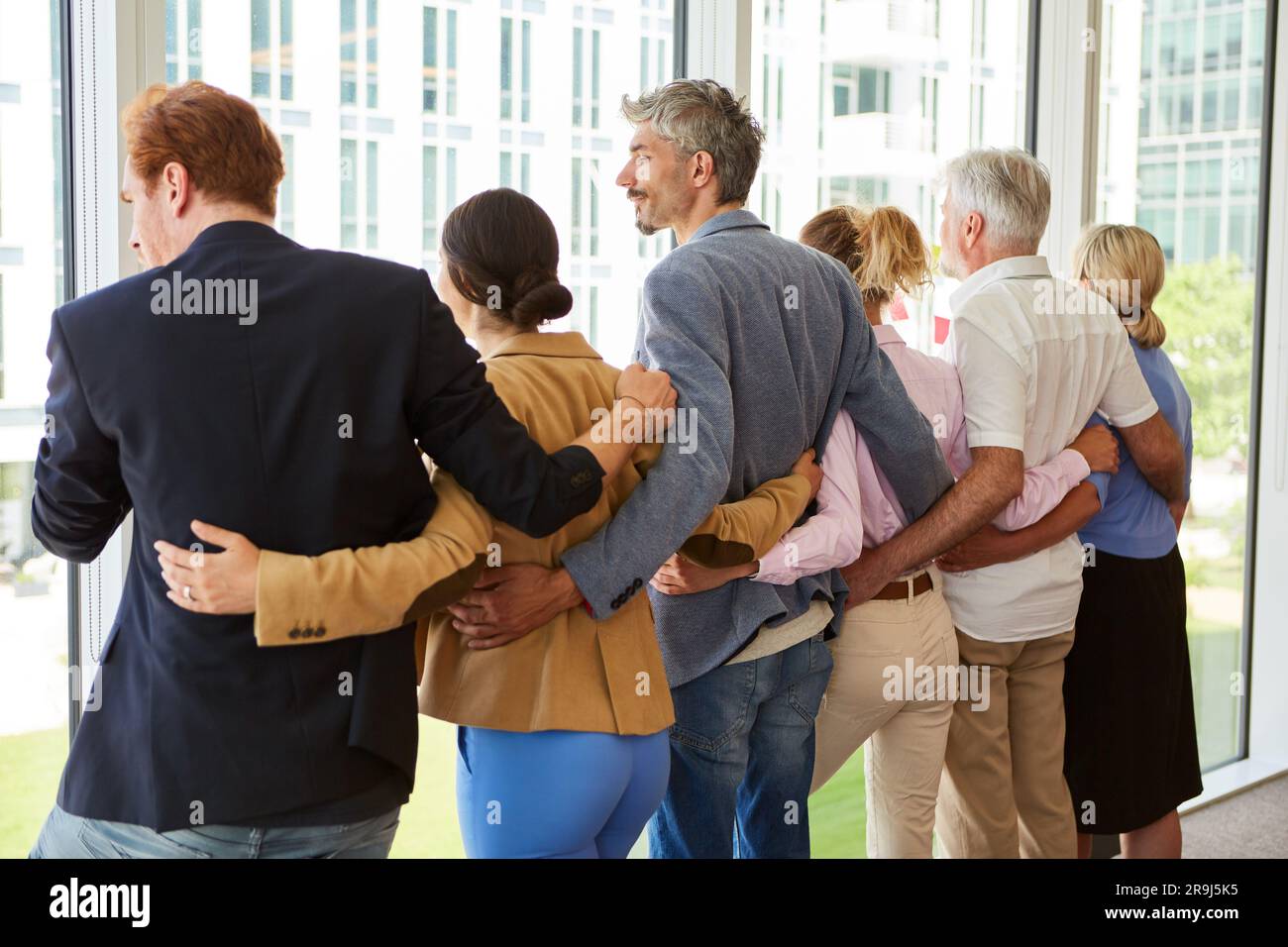 Rear view of business professionals standing with arms around Stock ...
