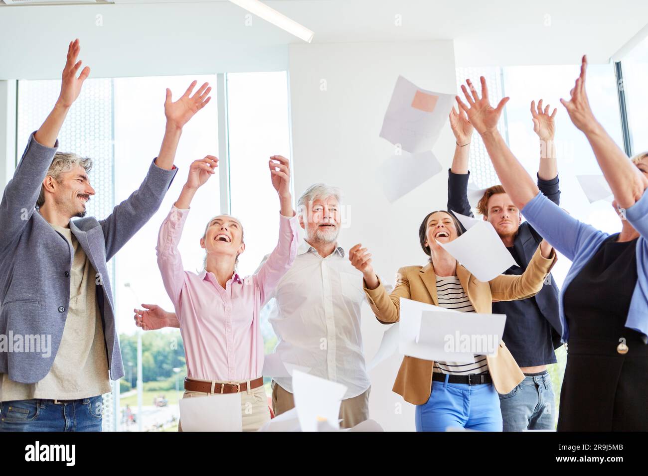 Happy business people cheering and throwing sheets of paper together in ...