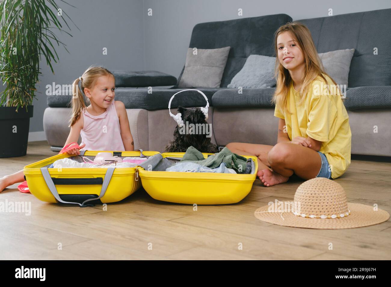 Children packing suitcase for travel and play with a dog. Sisters ...