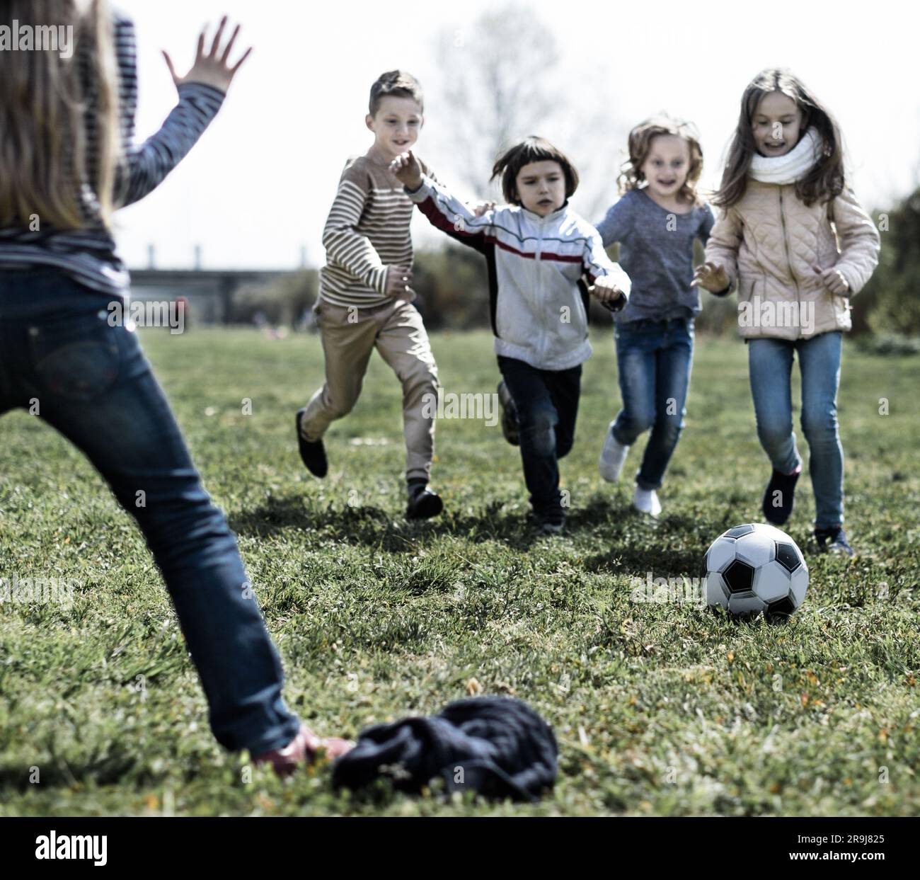 children run to soccer ball lying on grass Stock Photo - Alamy