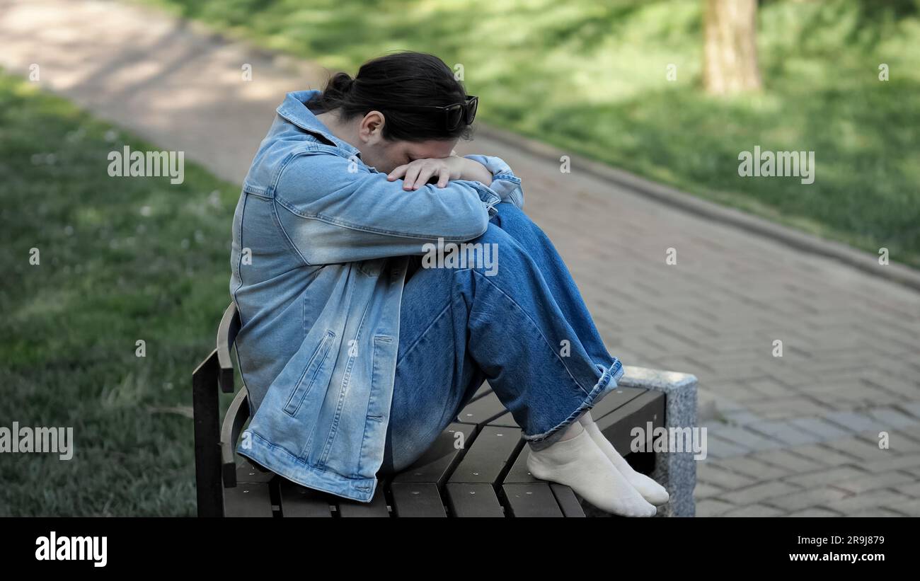 Depressed woman sitting on bench cries from loneliness Stock Photo - Alamy
