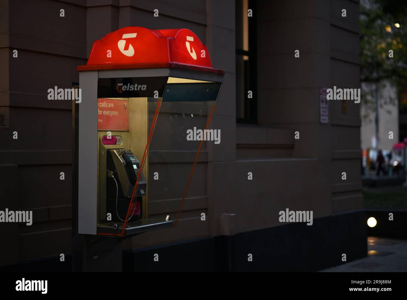 Telstra public phone box, or booth, with old orange branding, beside a ...