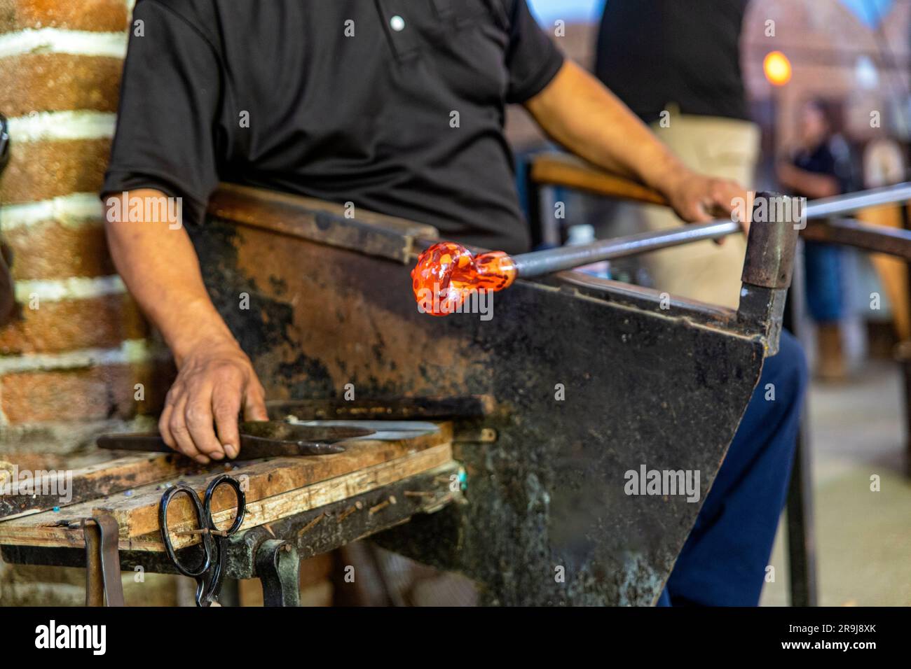 Old craftsman cutting and blowing the glass in fusing temperature to ...