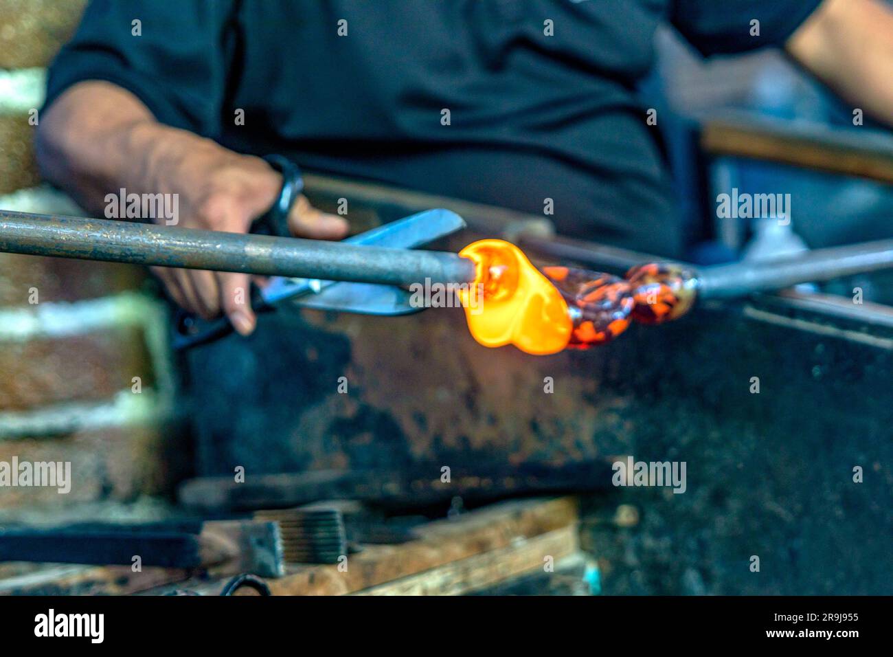 Old craftsman with scissors cutting and blowing the glass in fusing ...