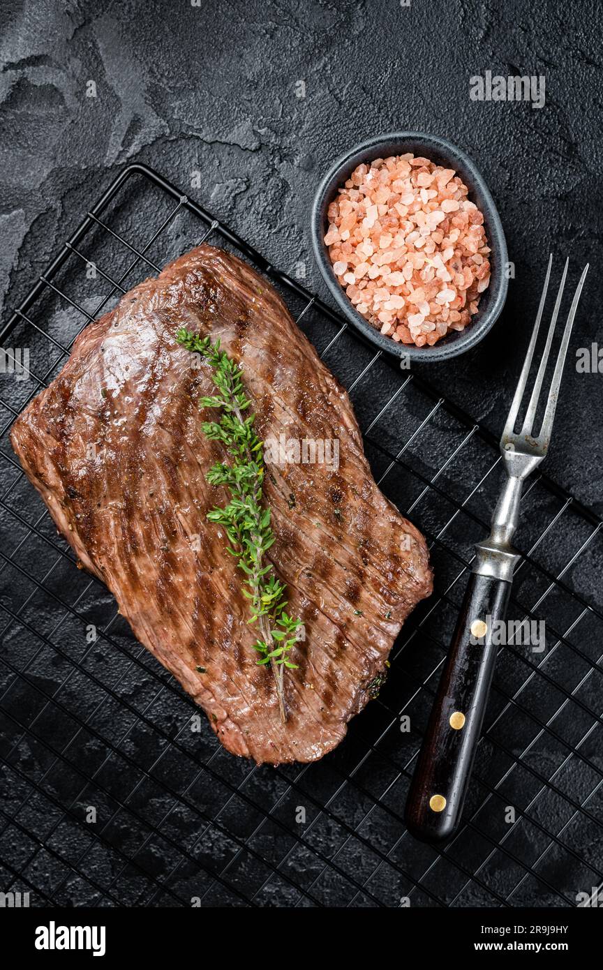 Roasted medium rare flank beef steak with thyme. Black background. Top ...