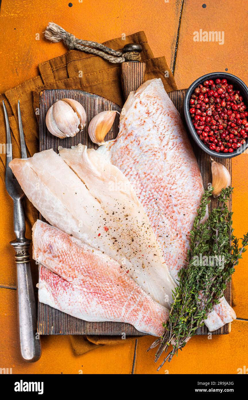 Uncooked ocean red perch fillet, redfish with herbs and spices. Orange ...